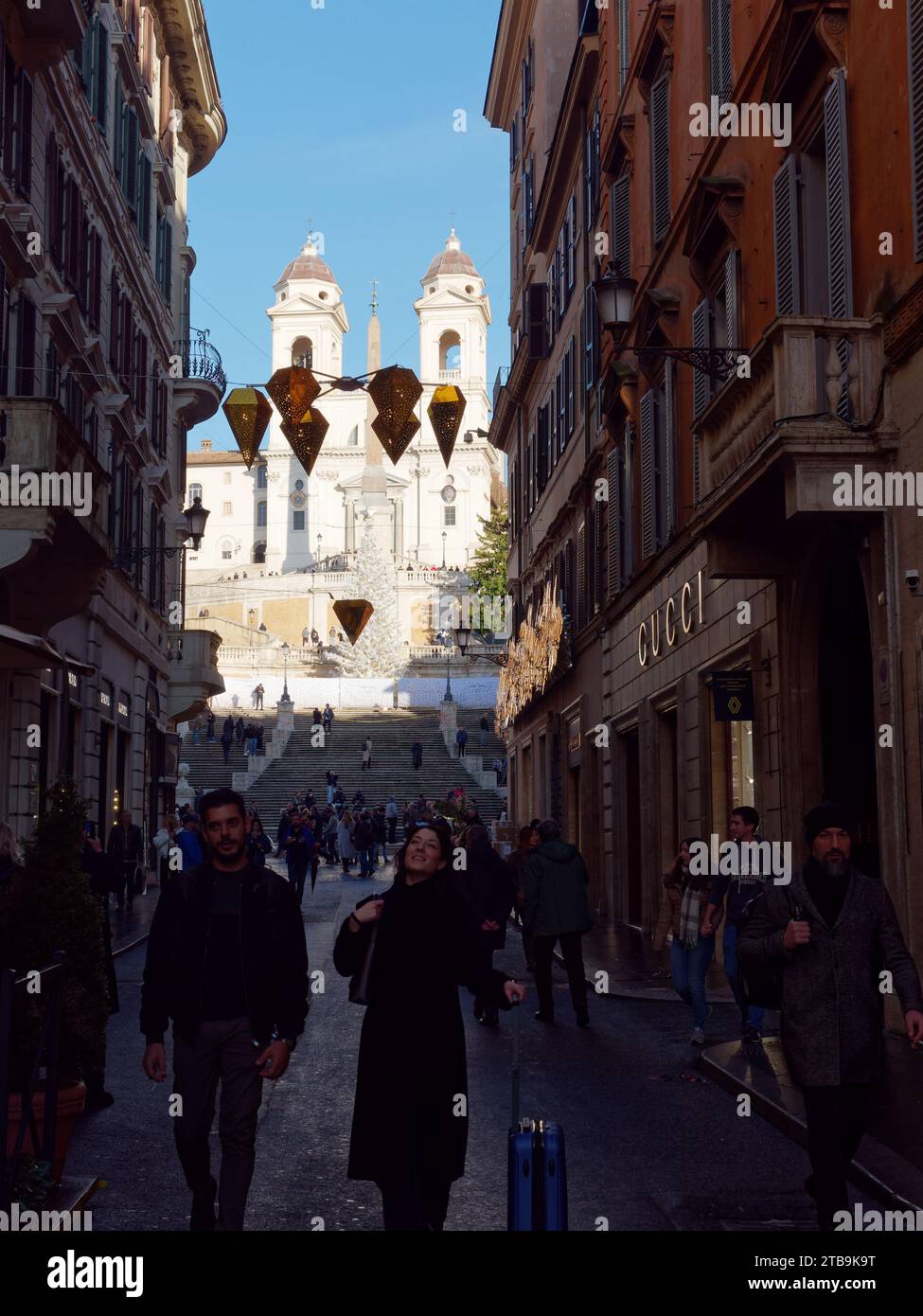 Tourists walk along a trendy retail street with the Spanish Steps ...