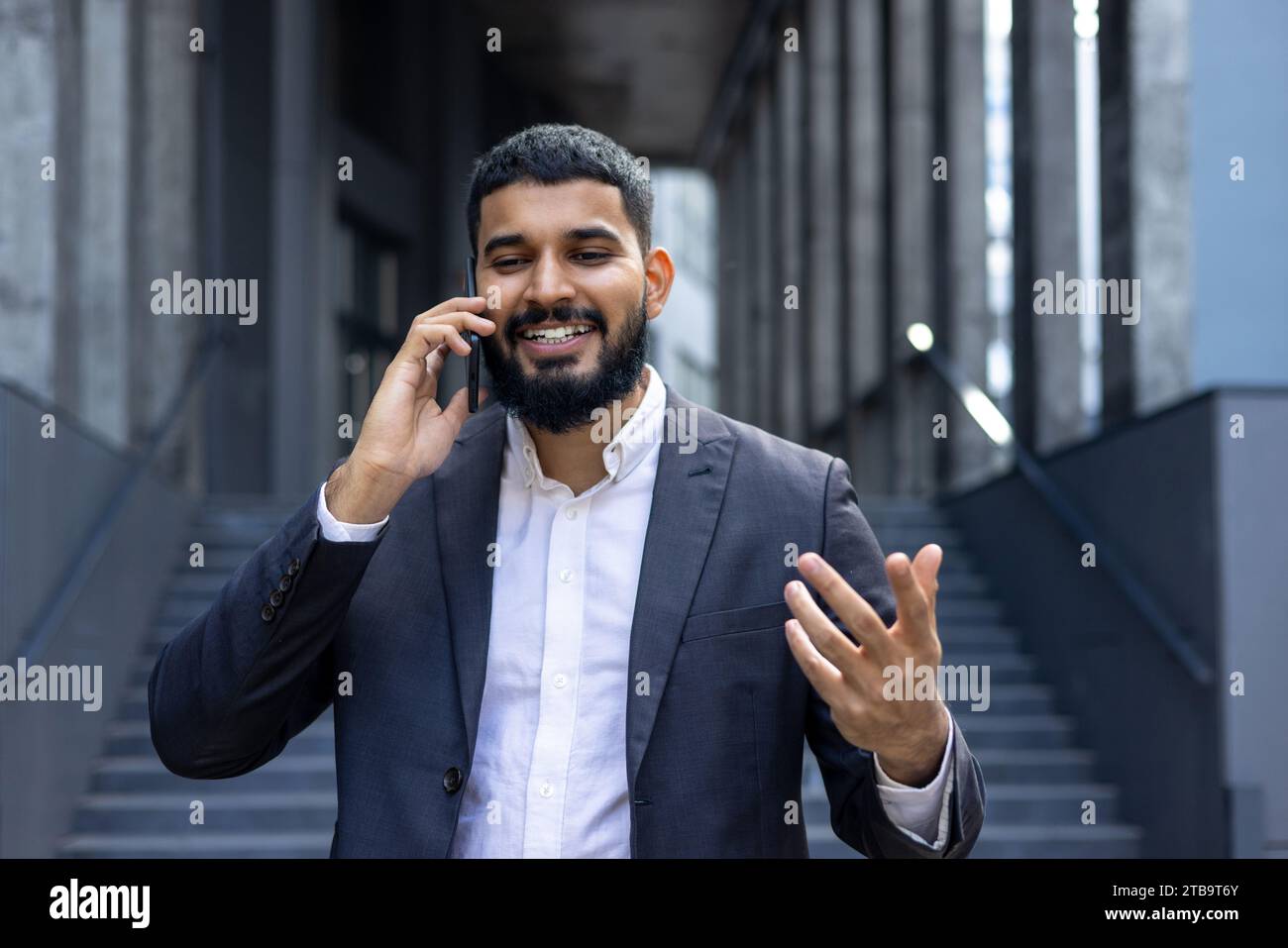 Smiling young Muslim man talking on the phone while standing outside an ...