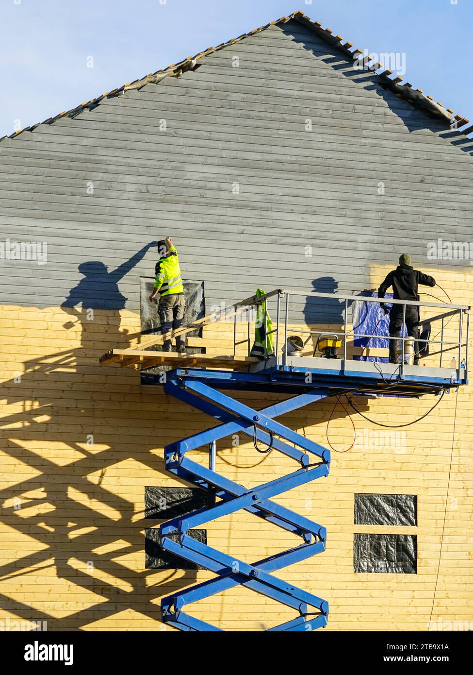 Residential house facade painting works after siding with wooden planks ...
