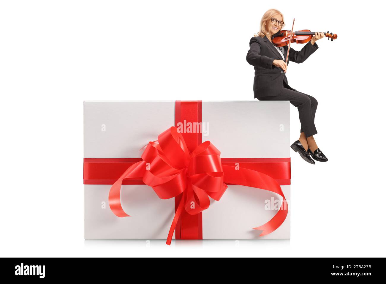 Woman sitting on a gift box and playing a violin isolated on white ...