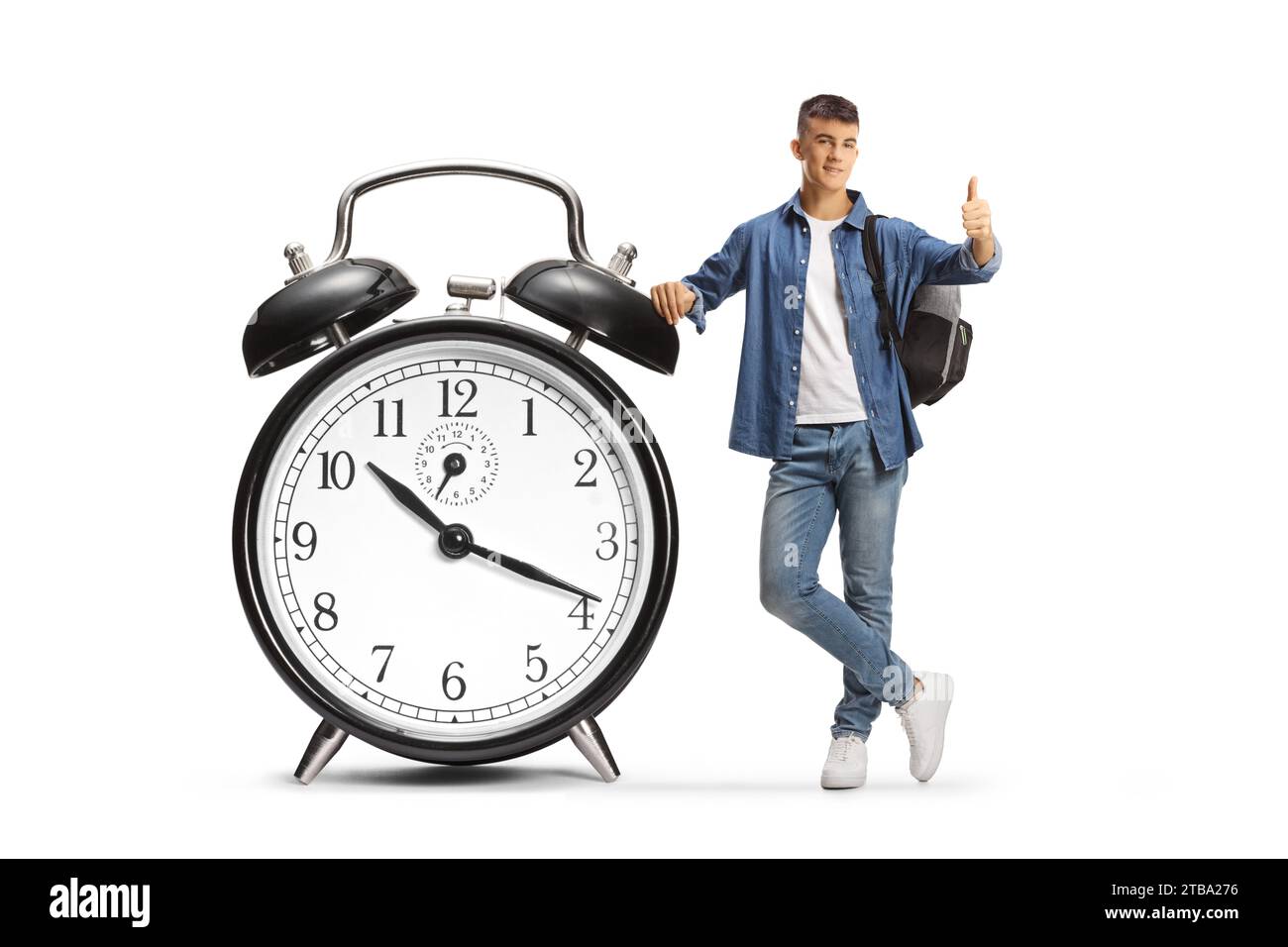Male student leaning on a big alarm clock and gesturing thumbs up ...