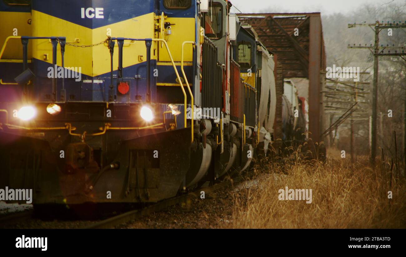 Freight train approaches and crosses a rusted iron truss bridge in a ...