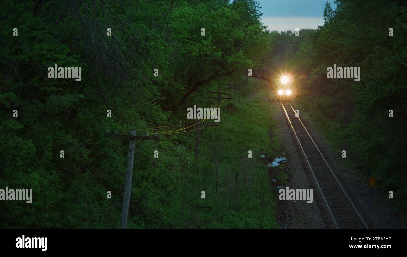 Freight train rounds the bend and emerges from the thickets and lush ...