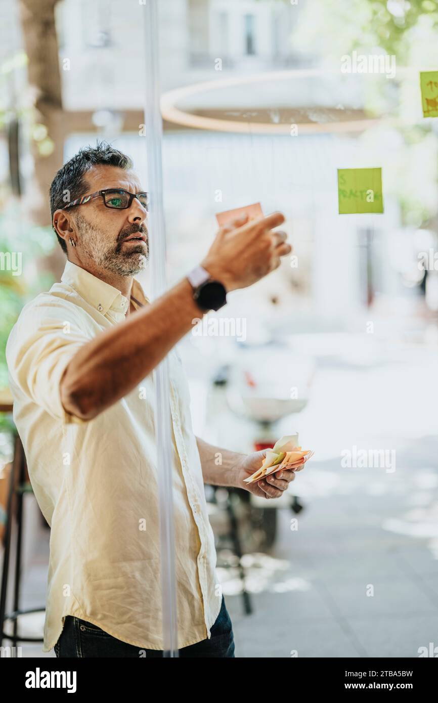 Businessman in a modern office collaborate, using sticky notes on a ...