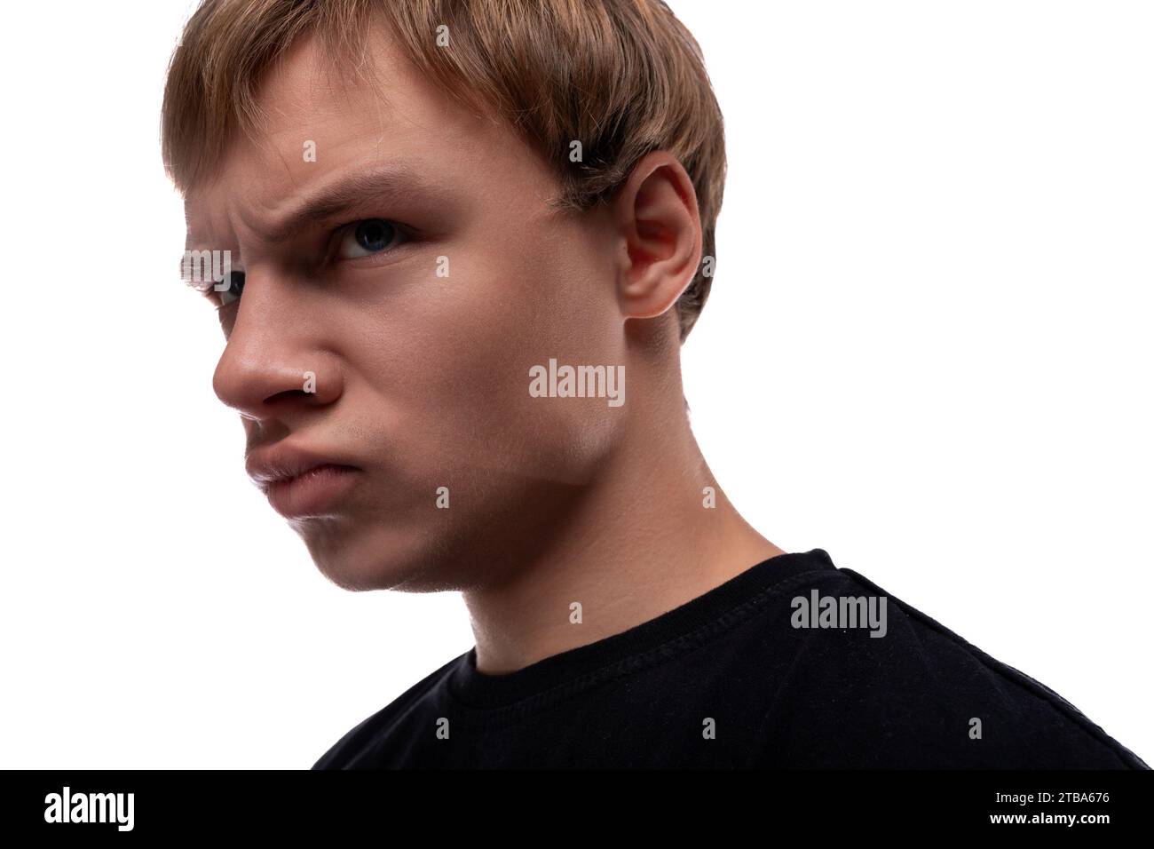 Headshot portrait of a suspicious blond Caucasian guy with blond hair looking from under his ...