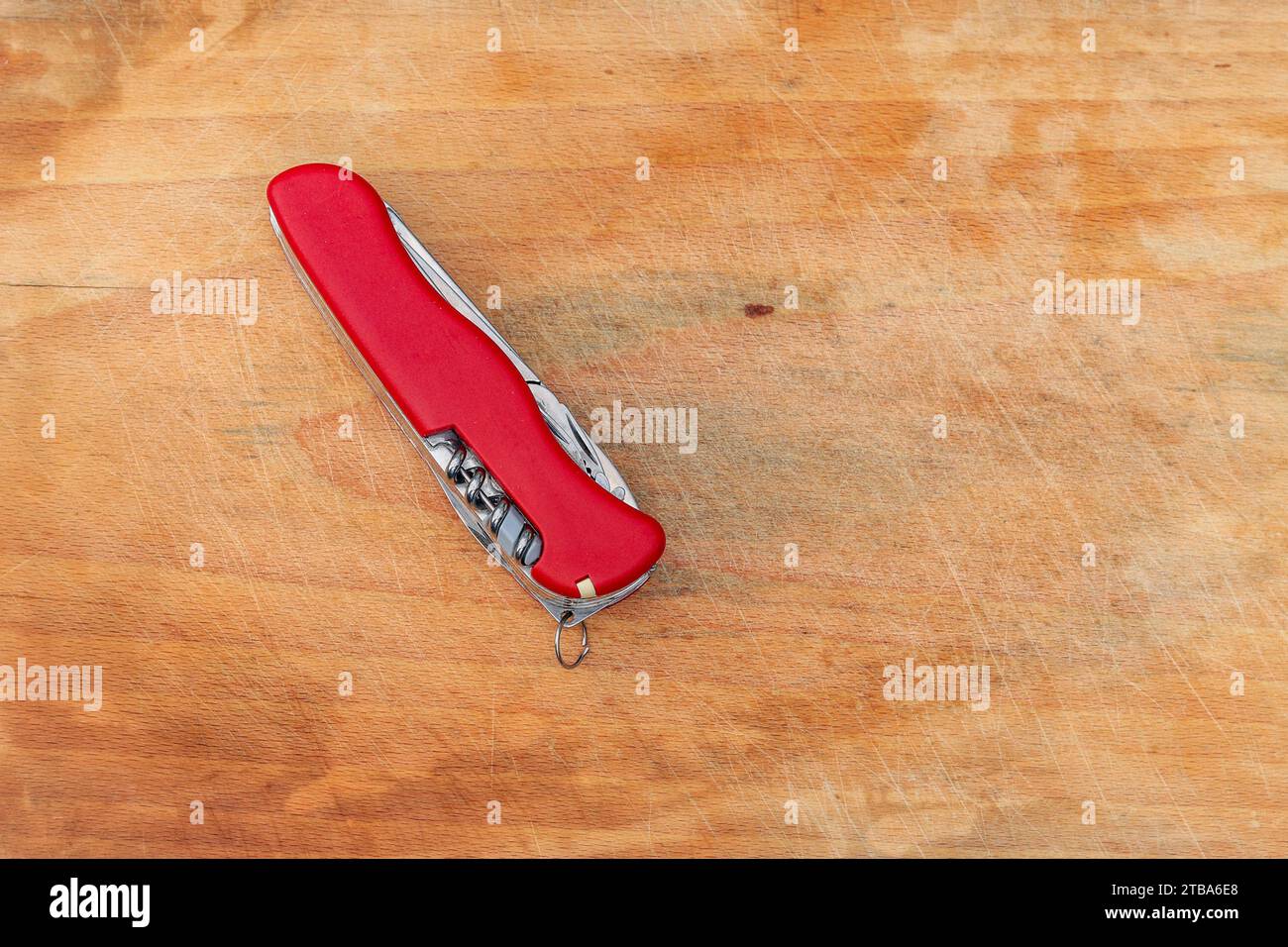 Red pocket knife and multi-tool on a wood board Stock Photo - Alamy