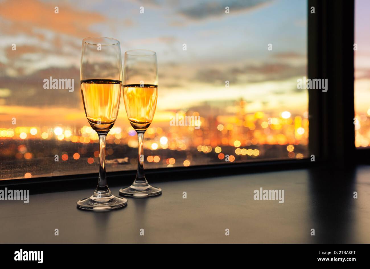 Pair of champagne glasses next to window with a beautiful golden city ...