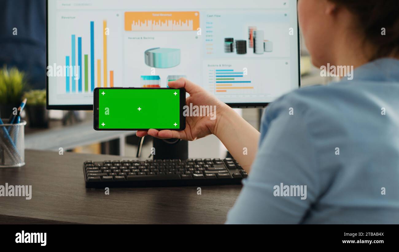 Worker Examines Empty Mockup Layout On Trendy Cellphone With Greenscreen Display Working On