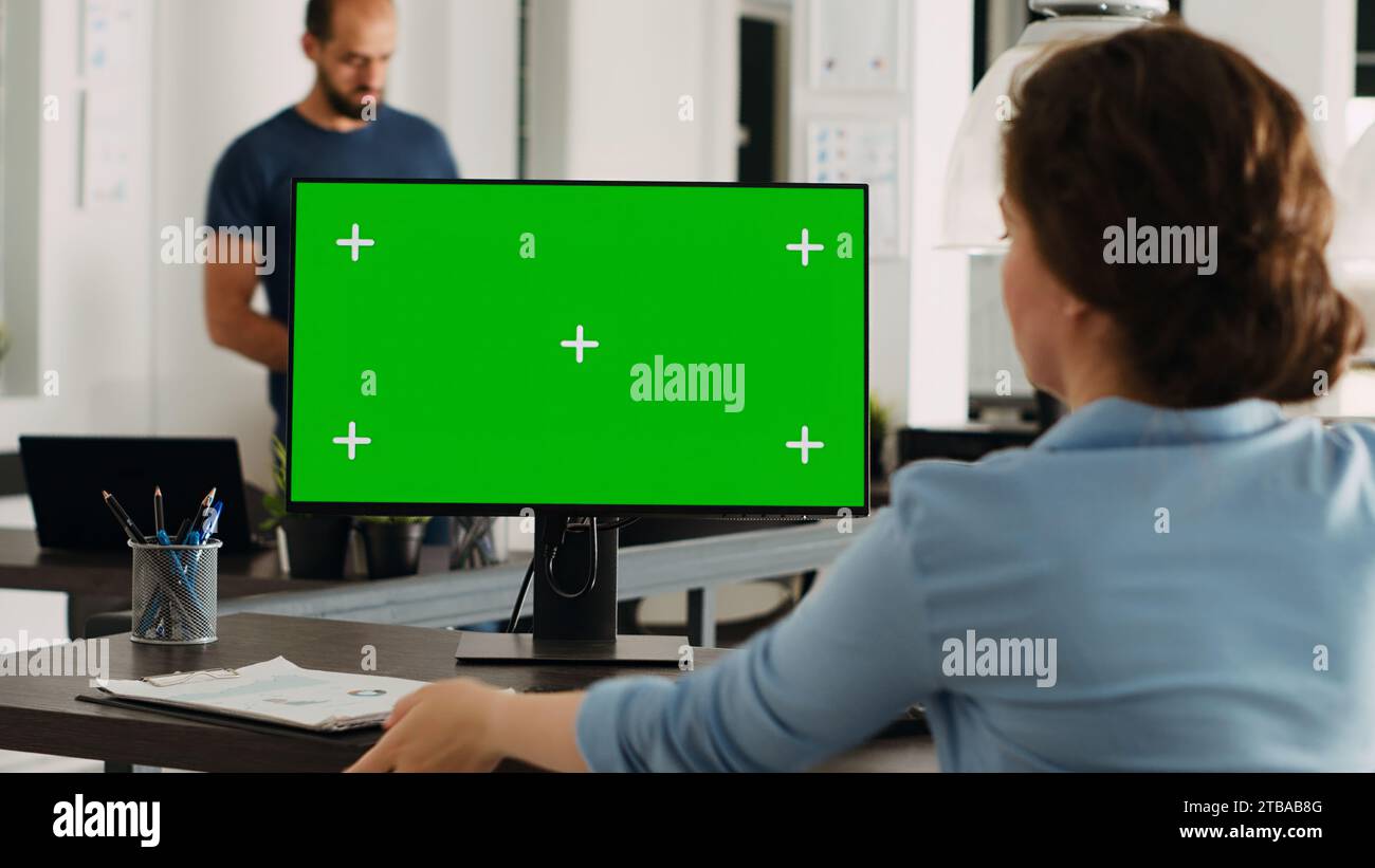Manager working with isolated greenscreen on computer at workstation ...
