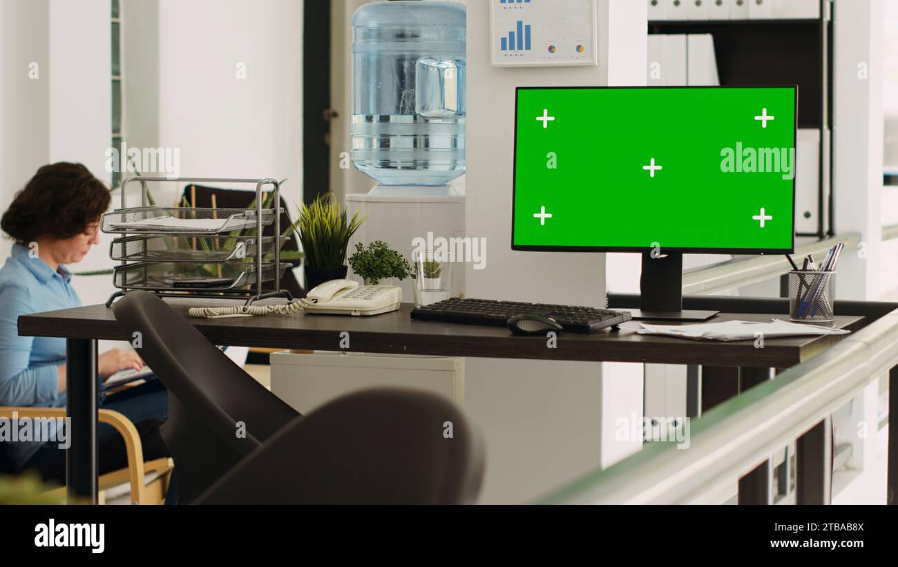 Empty workstation with greenscreen running on computer, open floor plan coworking space ...