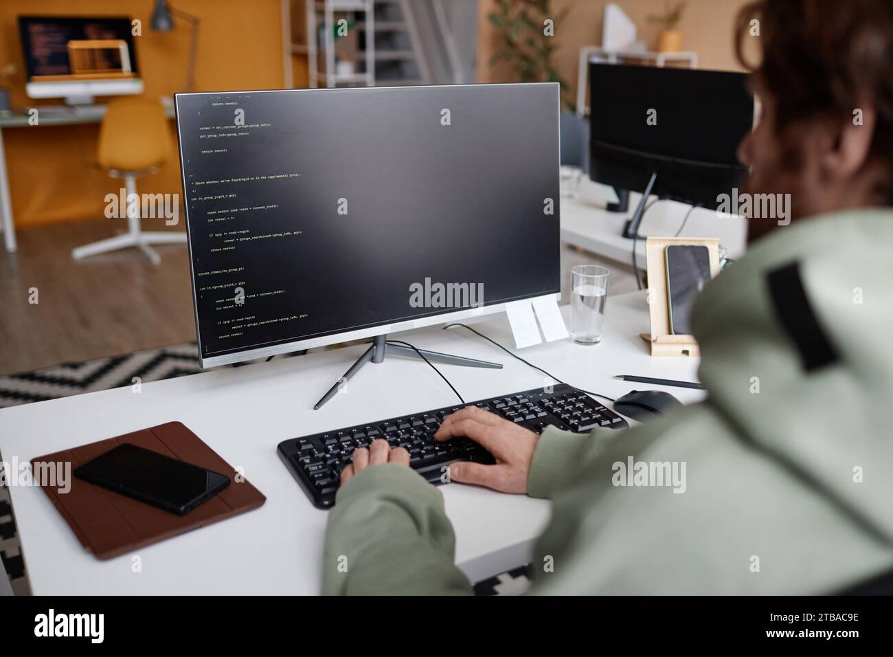 Over shoulder view at software developer writing code in office with ...