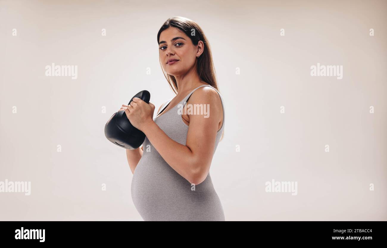Expecting mother in her third trimester exercises in a studio. She ...