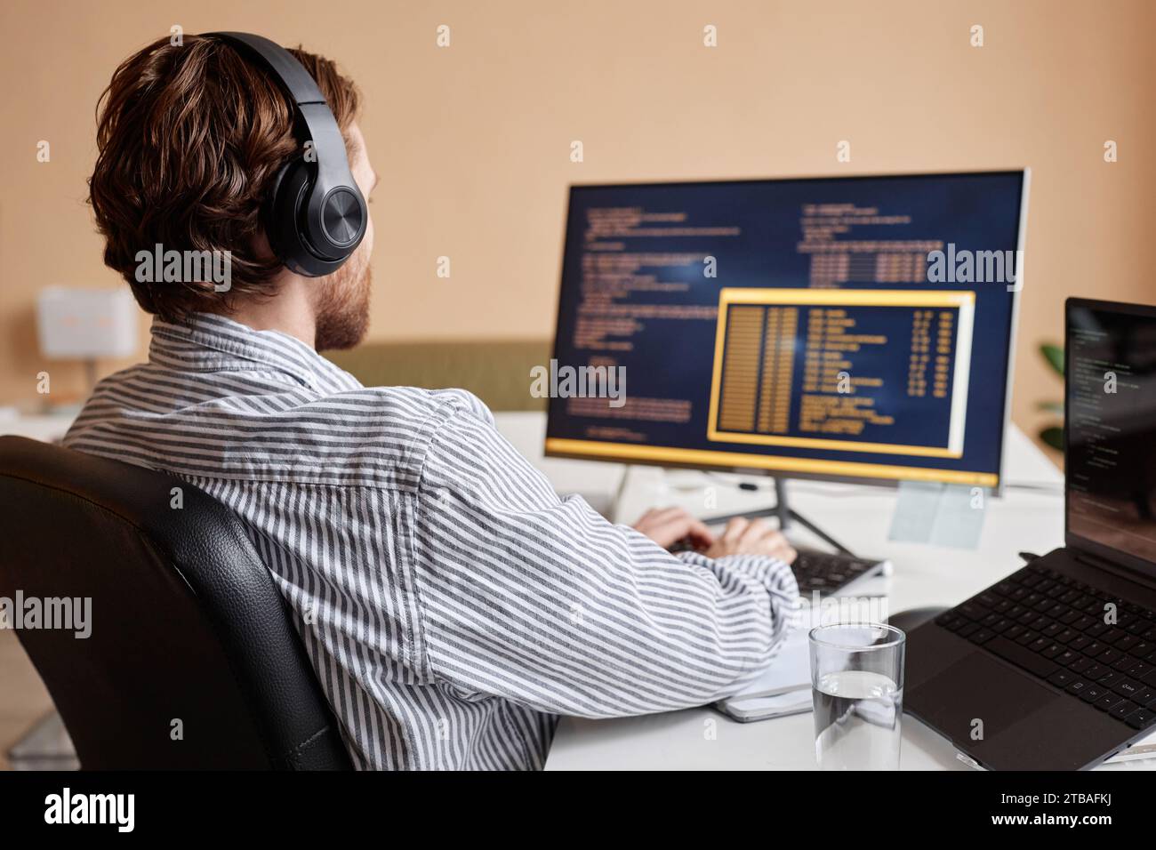 Male computer programmer writing code at office workplace and wearing ...