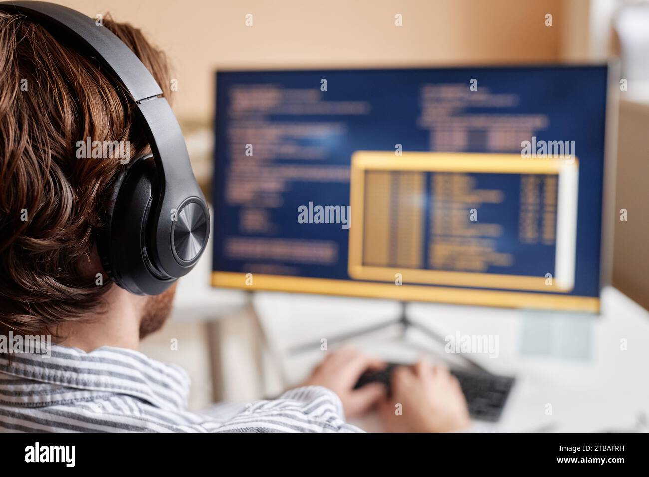 Over shoulder of male computer programmer writing code in office and ...