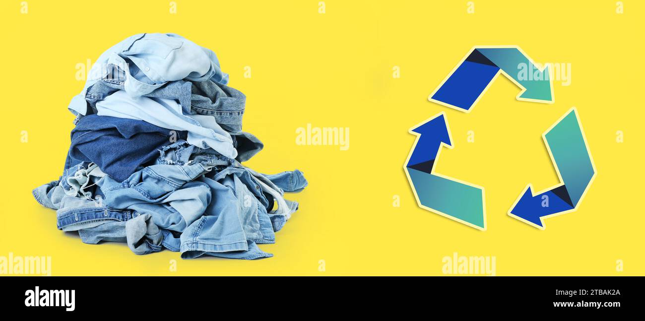 Heap of clothes and recycling symbol on yellow background. Ecology ...