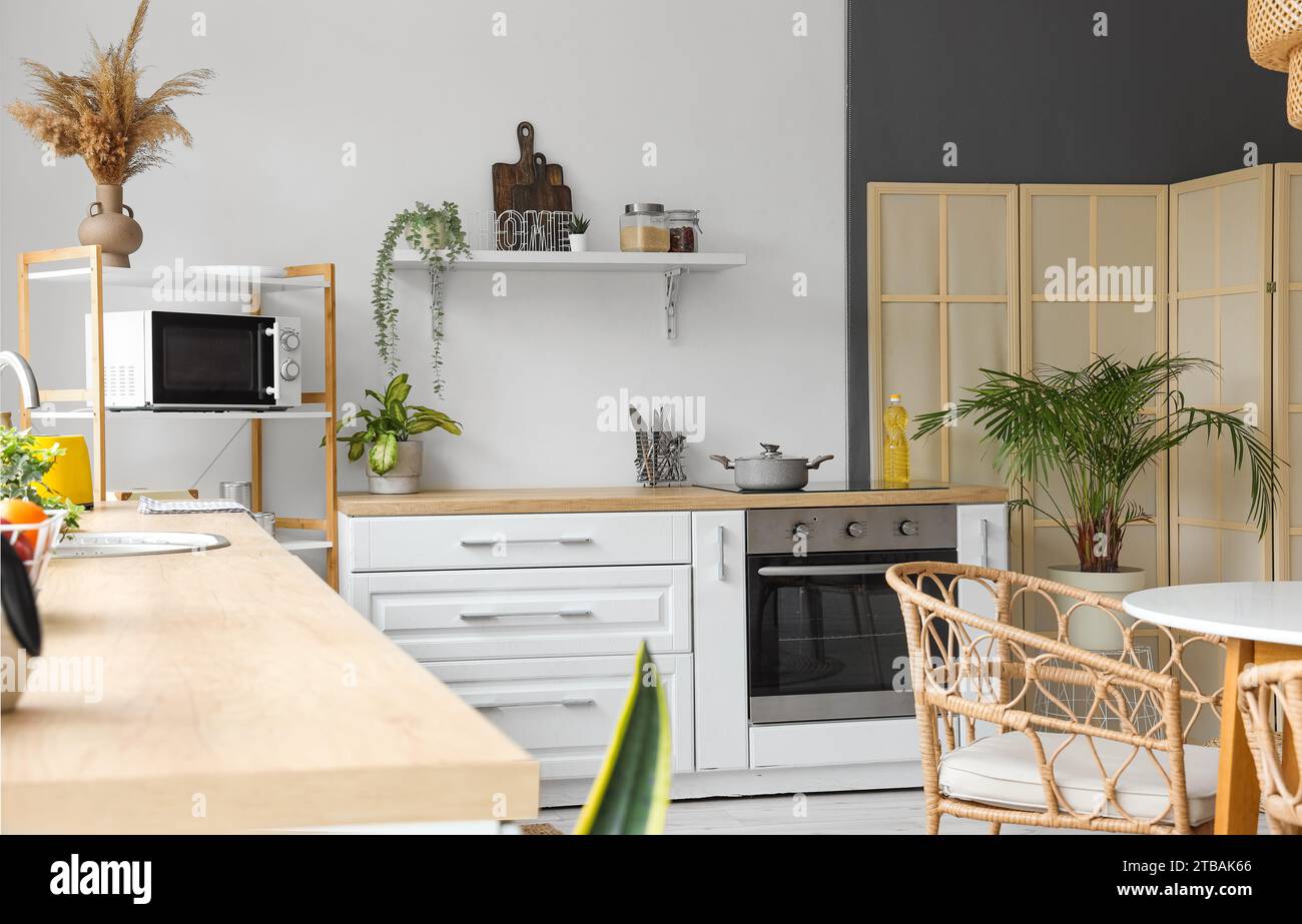Interior of modern kitchen with white counters and microwave oven on ...