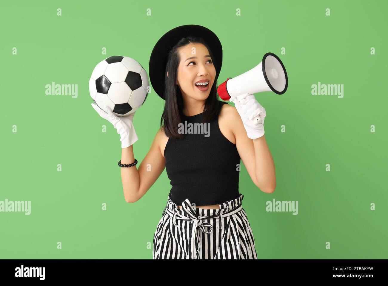 Female Asian football fan with megaphone on green background Stock ...