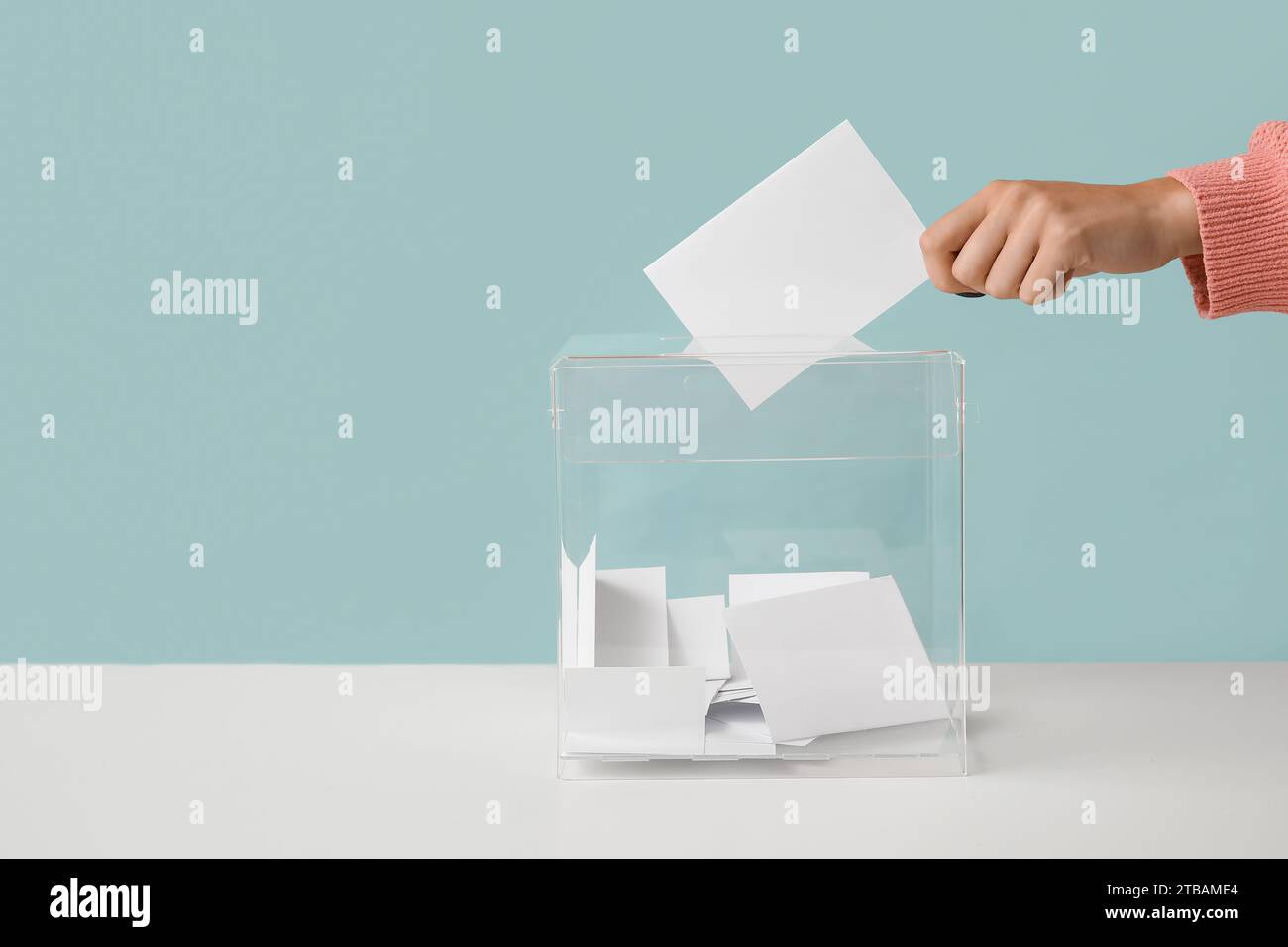 Hand putting voting paper in ballot box on light blue background Stock ...