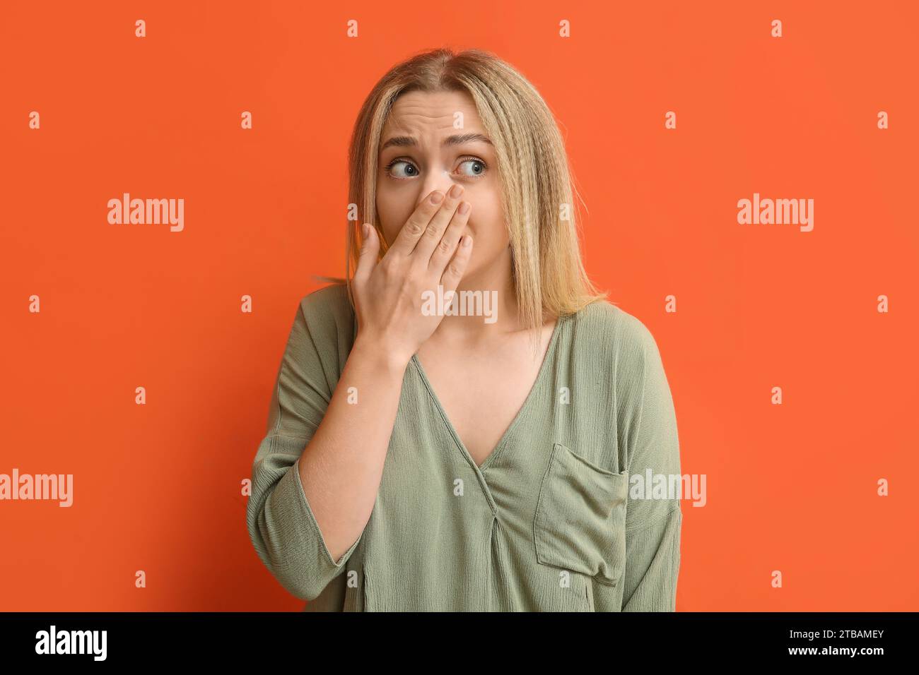 Embarrassed young woman on orange background Stock Photo - Alamy