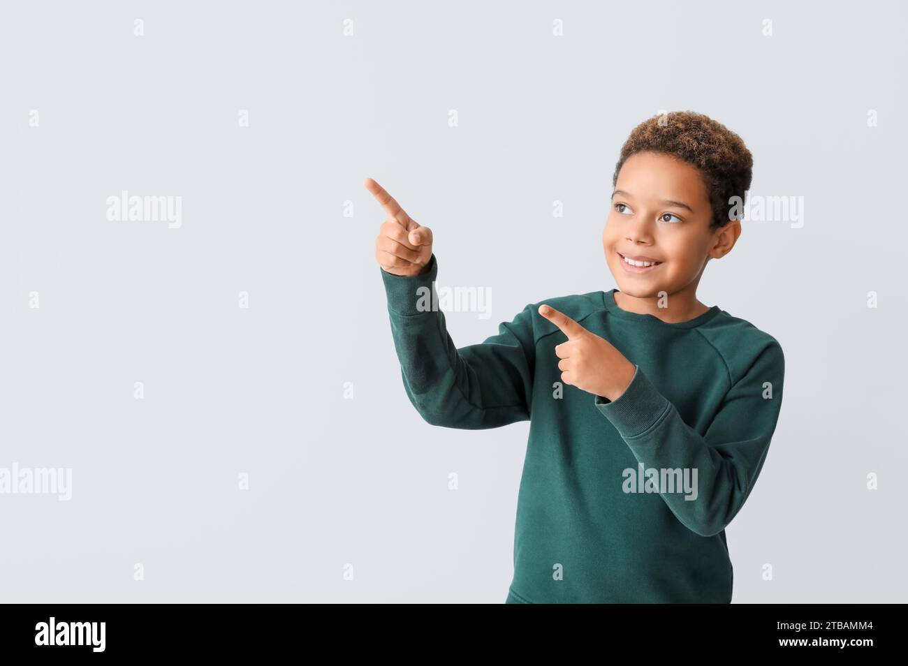 Little African-American boy pointing at something on white background ...
