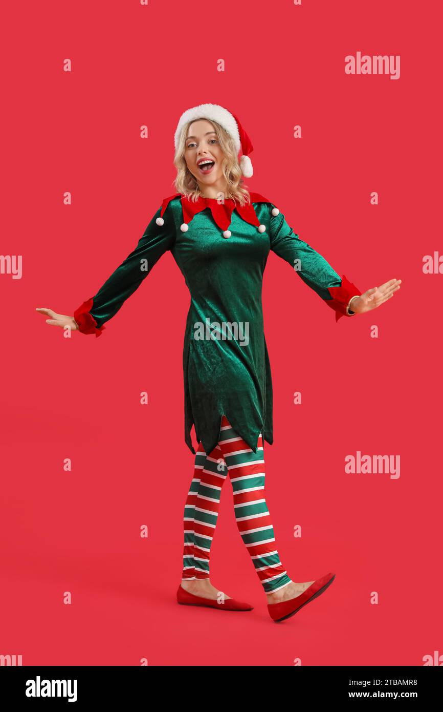 Happy young woman dressed as elf on red background Stock Photo - Alamy