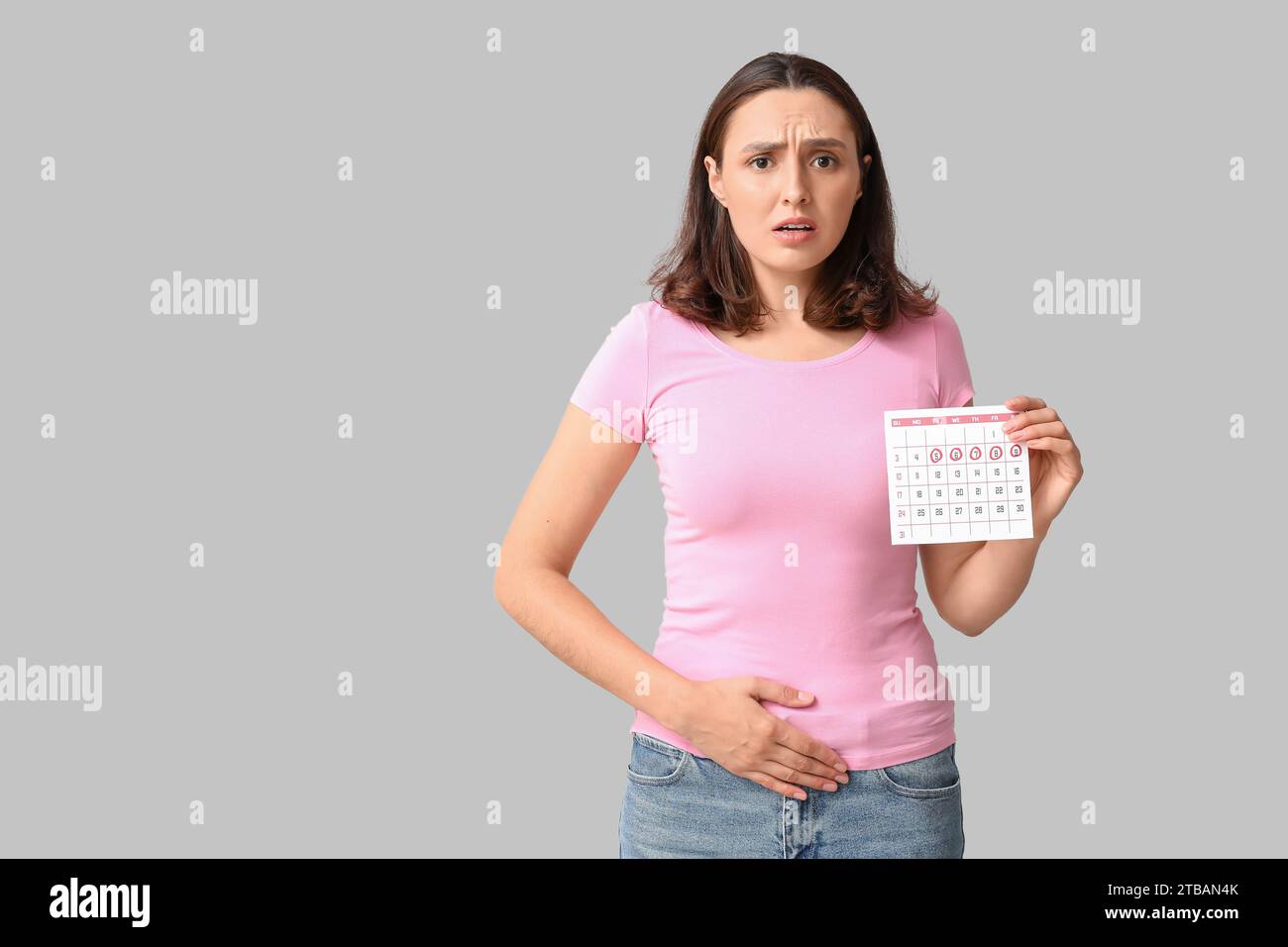 Beautiful young woman holding calendar with marked days of menstruation ...