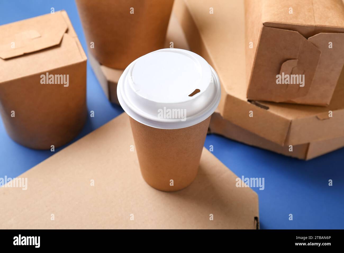 Takeaway paper cup and different boxes on blue background, closeup ...