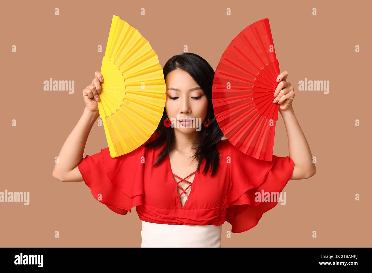 Beautiful young Asian woman with fans on brown background. Chinese New ...