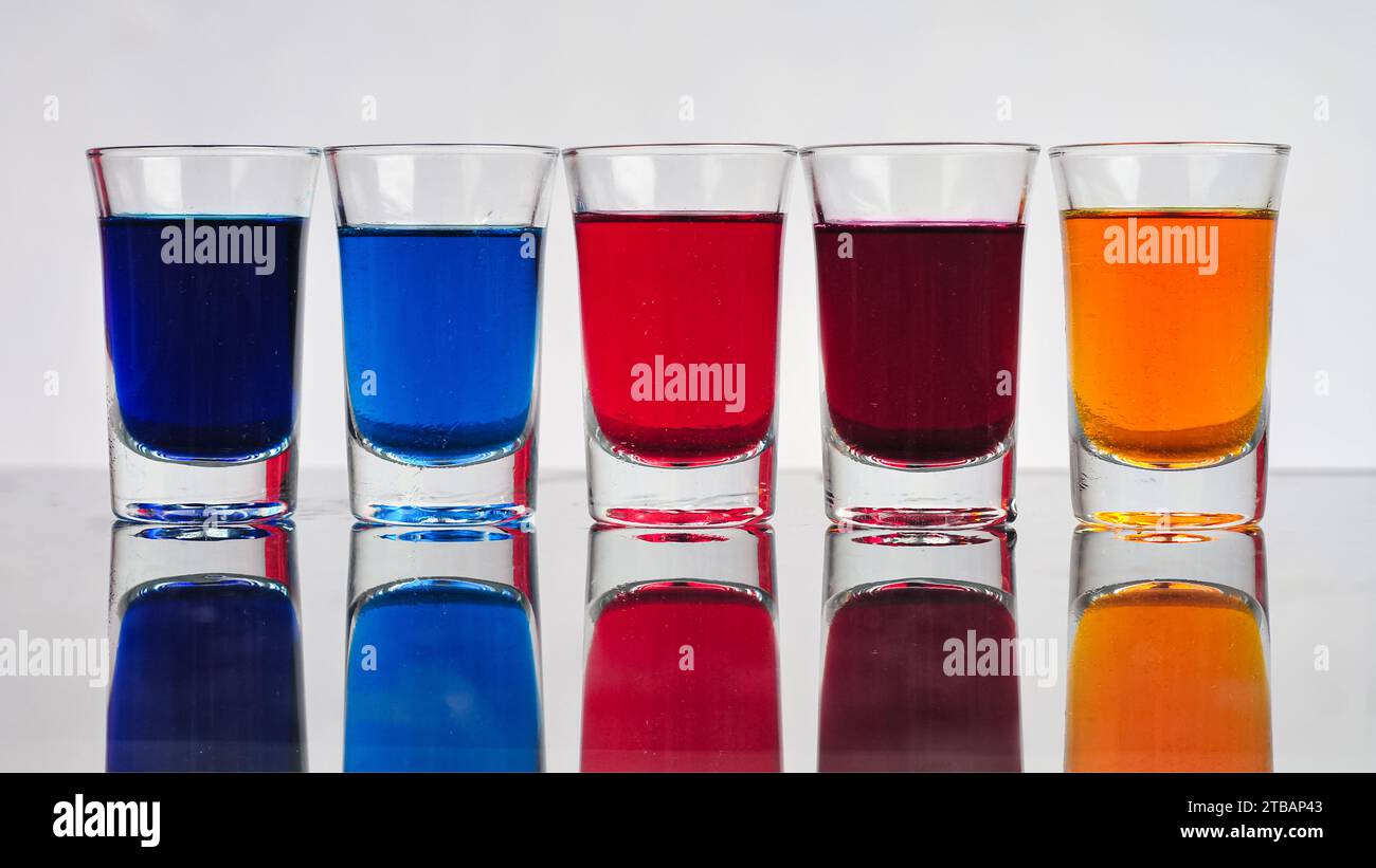 Small glasses filled with colorful water are neatly arranged on an ...
