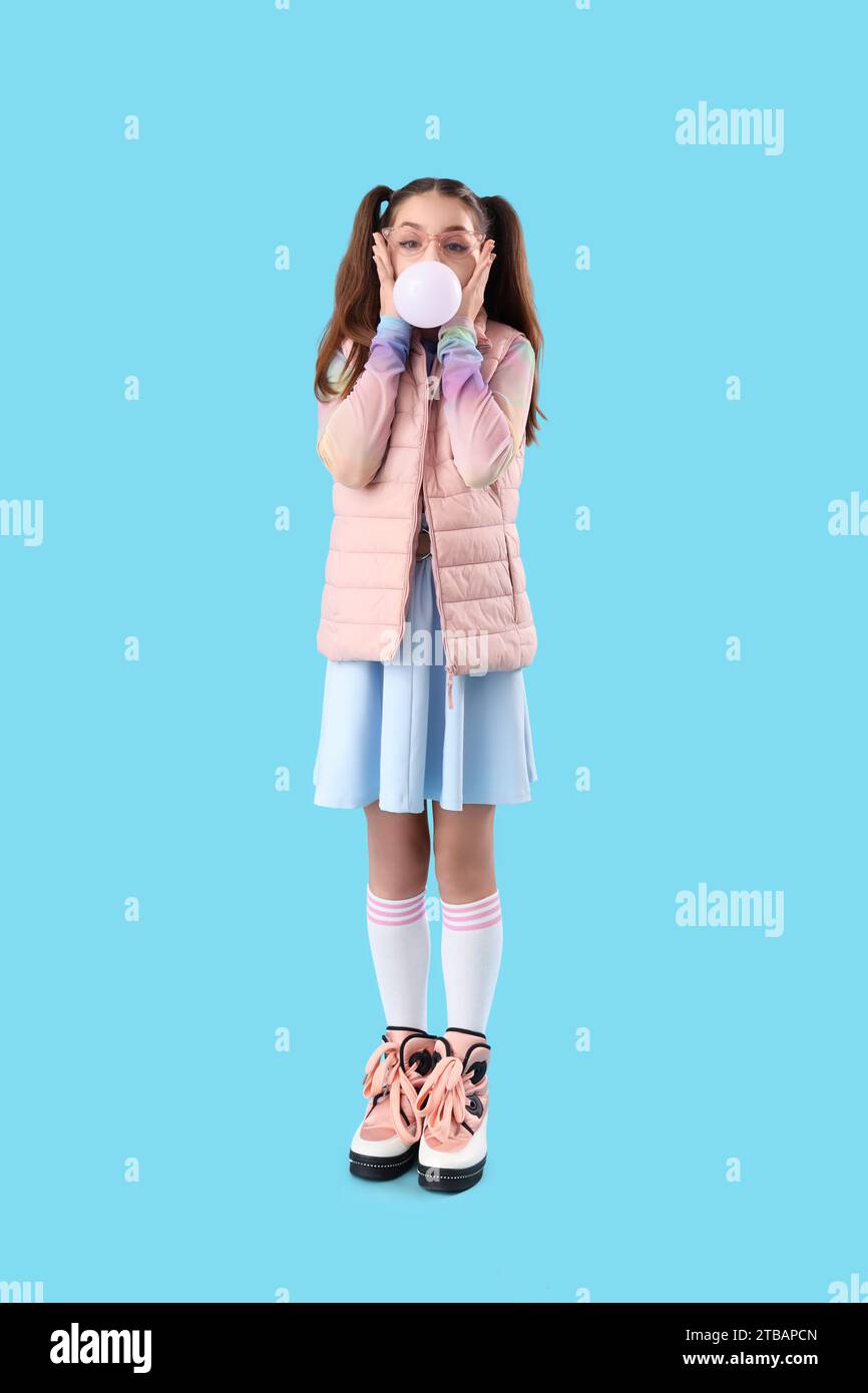 Trendy girl blowing bubble gum on blue background Stock Photo - Alamy