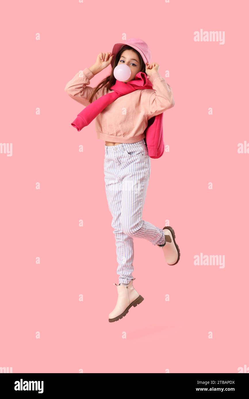 Trendy girl blowing bubble gum while jumping on pink background Stock ...