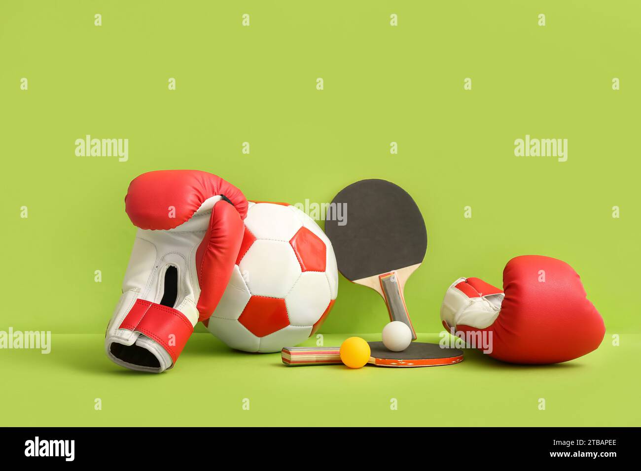 Soccer ball with boxing gloves and ping pong rackets on green ...