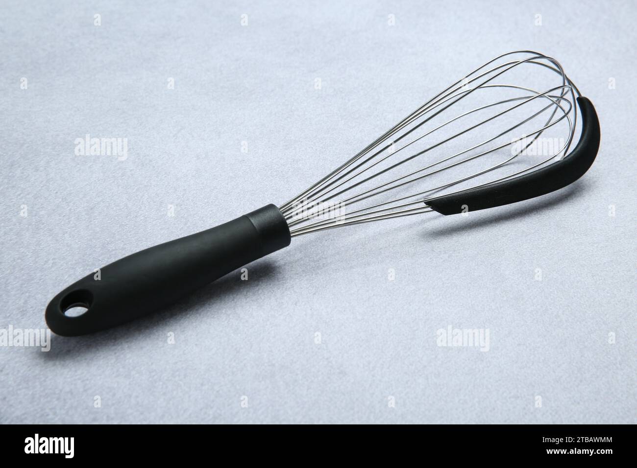 Metal whisk on gray table. Kitchen tool Stock Photo - Alamy