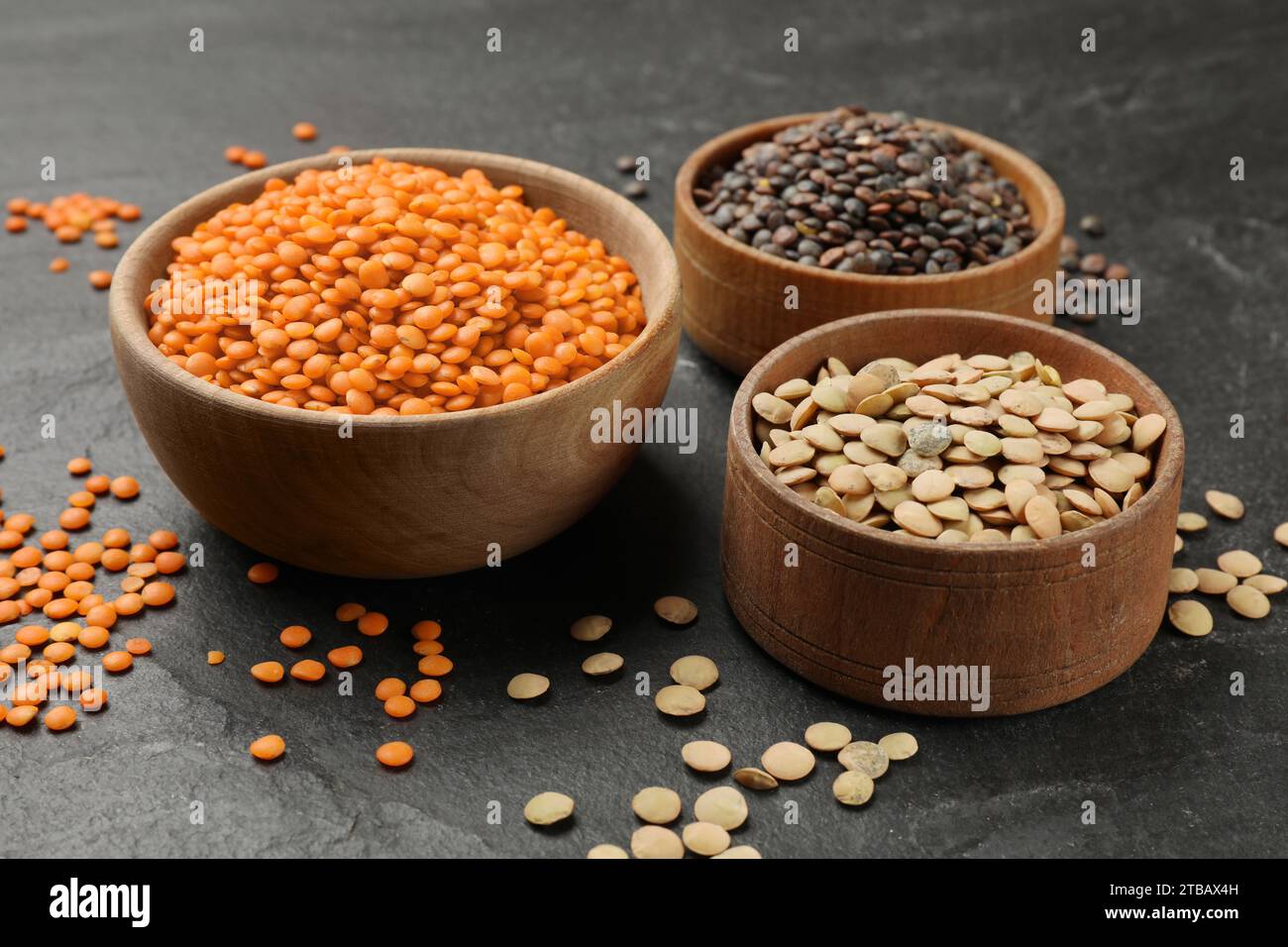 Different types of lentils in bowls on grey textured table Stock Photo ...