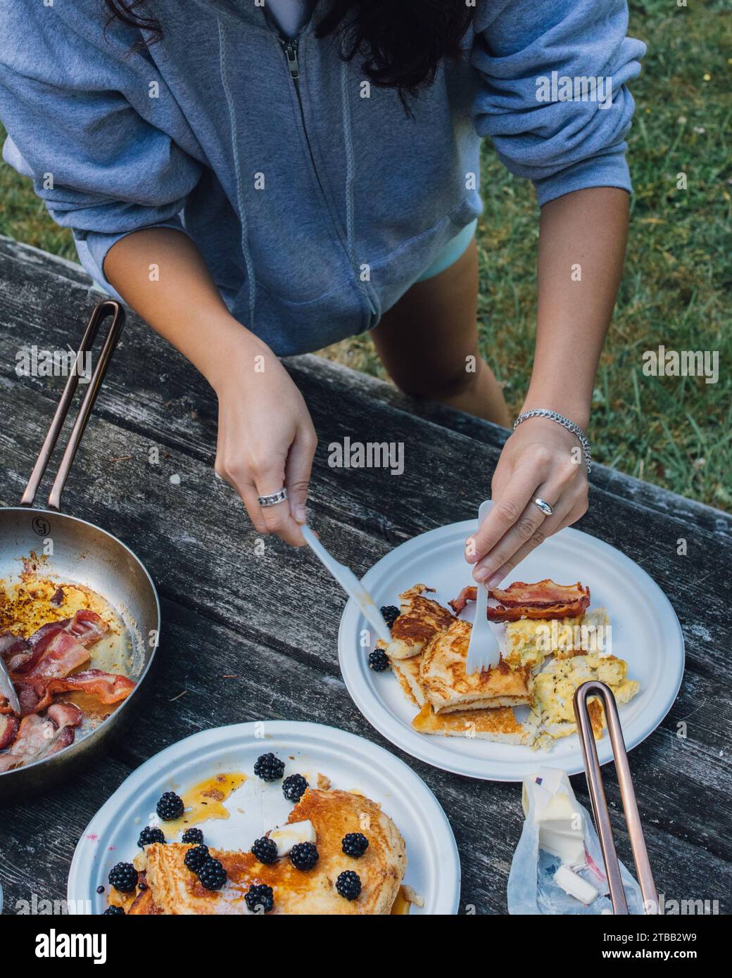 camping breakfast: woman serving herself a helping of pancakes ...