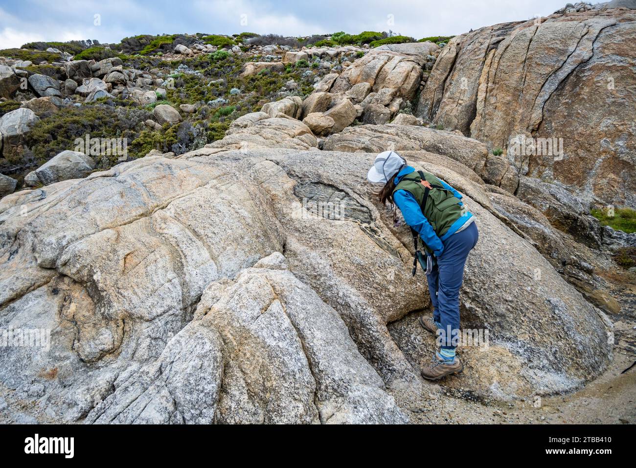 A female geologist taking a close look at the granite outcrops along ...