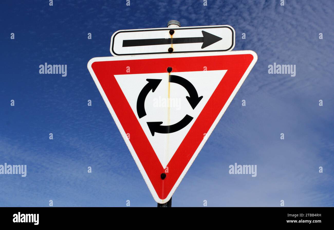 Roundabout traffic circle road sign against a blue sky background with ...