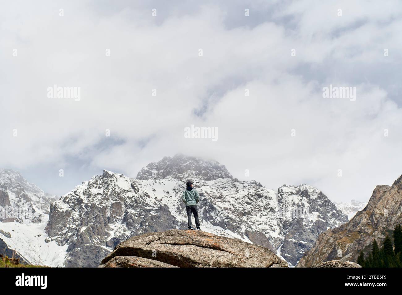 rear view of asian man male traveler standing on top of a rock looking ...