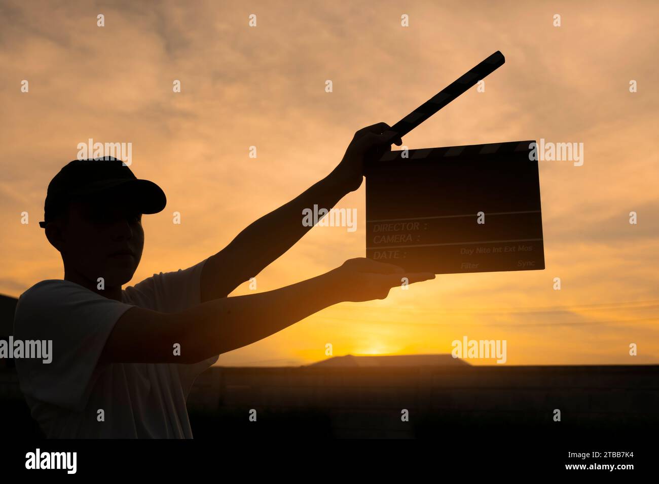 Teenage boy holding a film slate or film clapper board at sunset. new ...