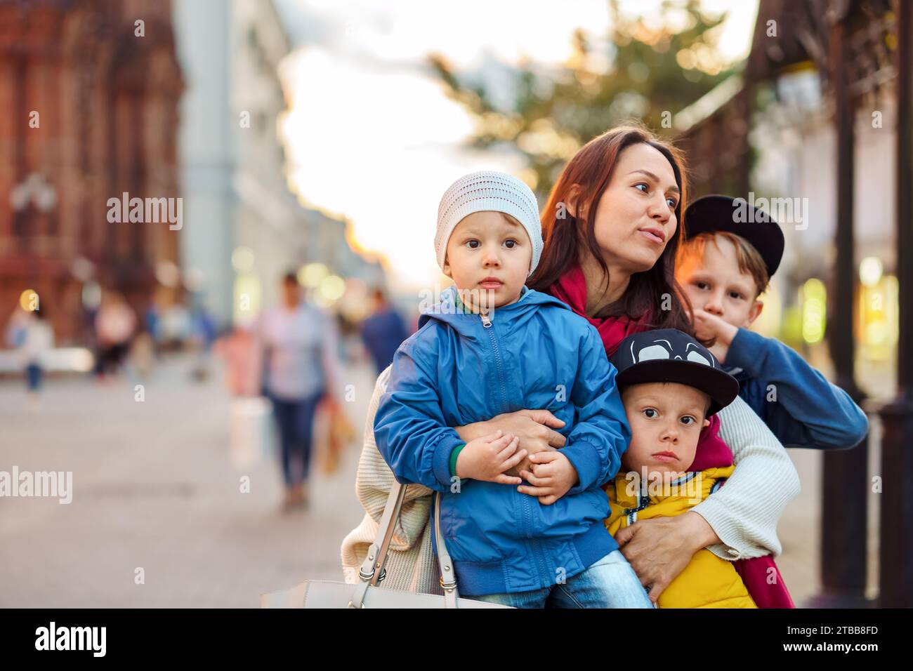 Busy mother with children group stands on city street. Woman and cute ...