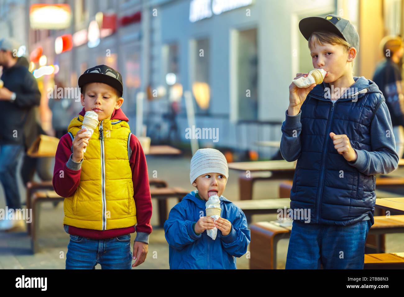 Happy brothers enjoy tasty ice cream together in evening city. Children ...