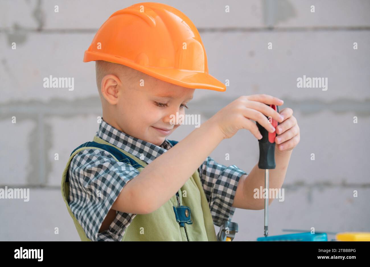 Child play with supplies, tools saw, hammer, screwdriver, helmet ...