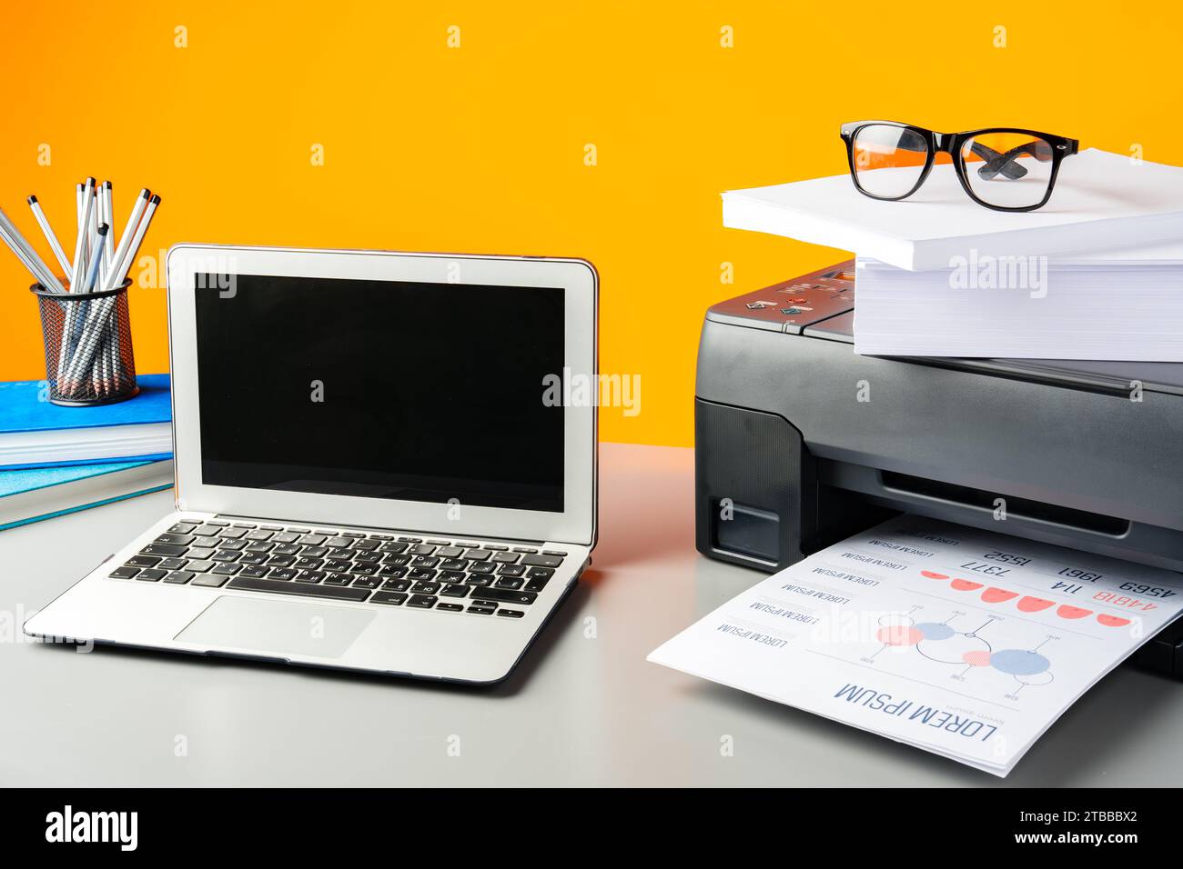 Laser printer and laptop on desk against yellow background Stock Photo ...