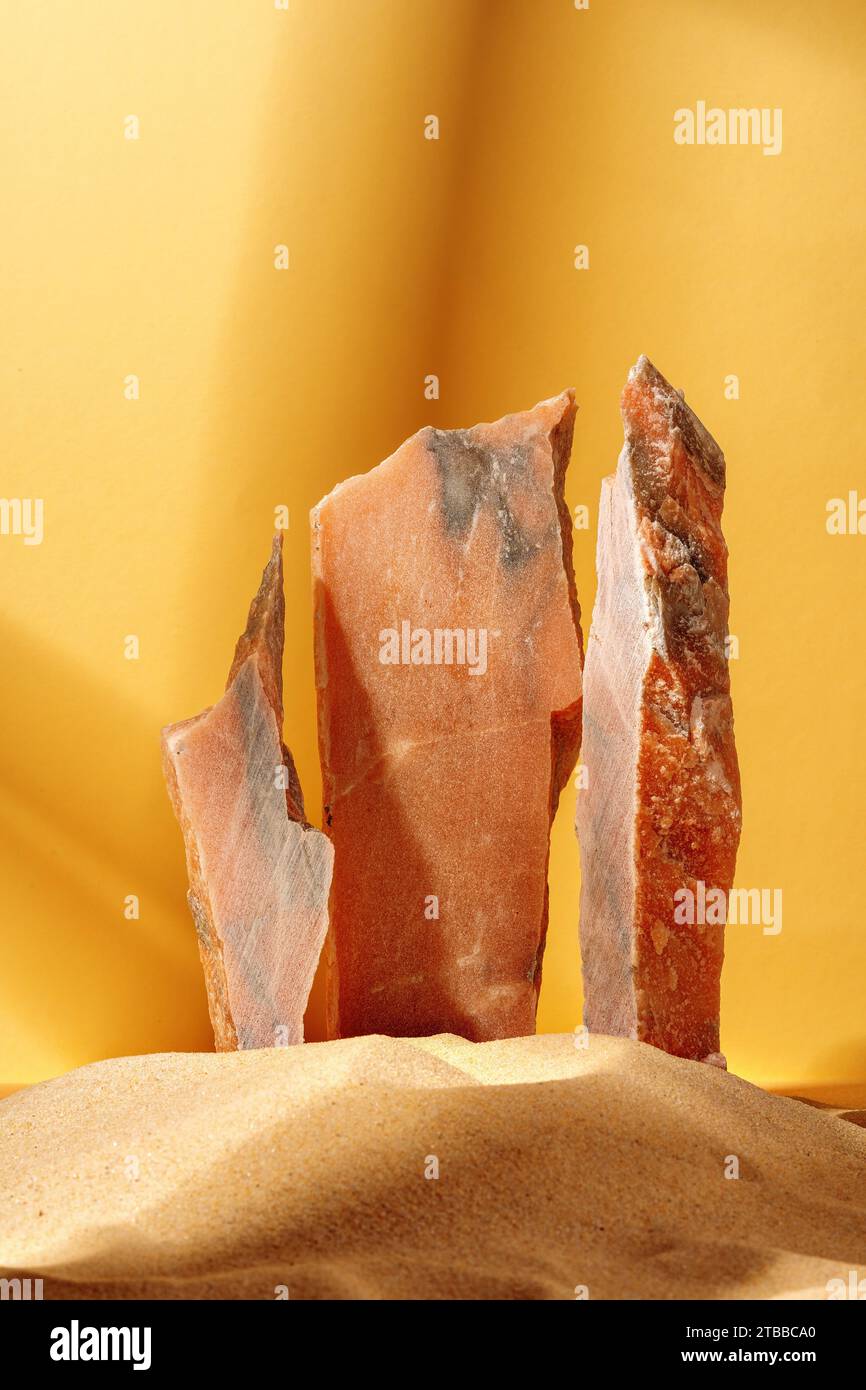 Marble rocks in sand against yellow background Stock Photo - Alamy