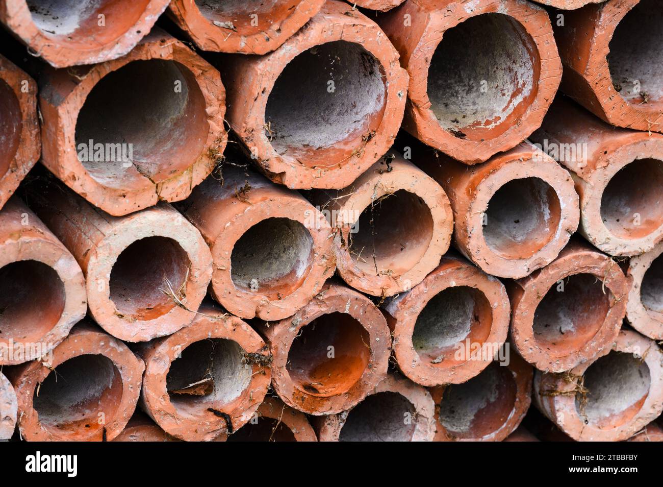 Drainage old clay pipes for sewage stacked in a texture with holes ...