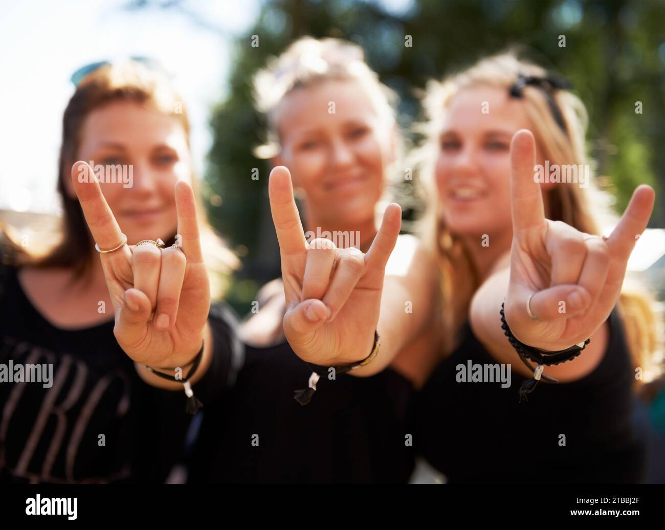 Friends, portrait and women with rocker hands at a music festival ...