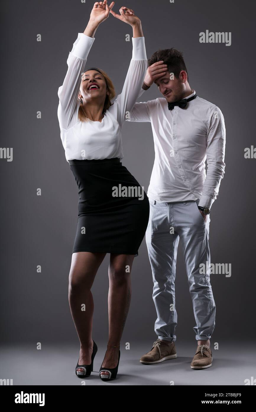 Jubilant black woman dances as the white man beside her facepalms Stock Photo - Alamy