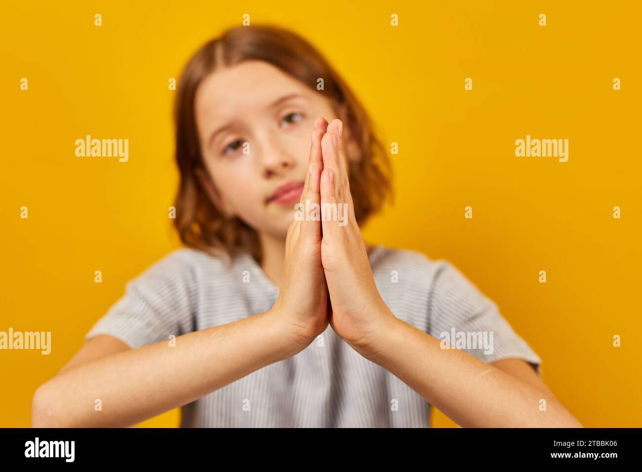 Pleading teen girl on yellow studio background Stock Photo - Alamy