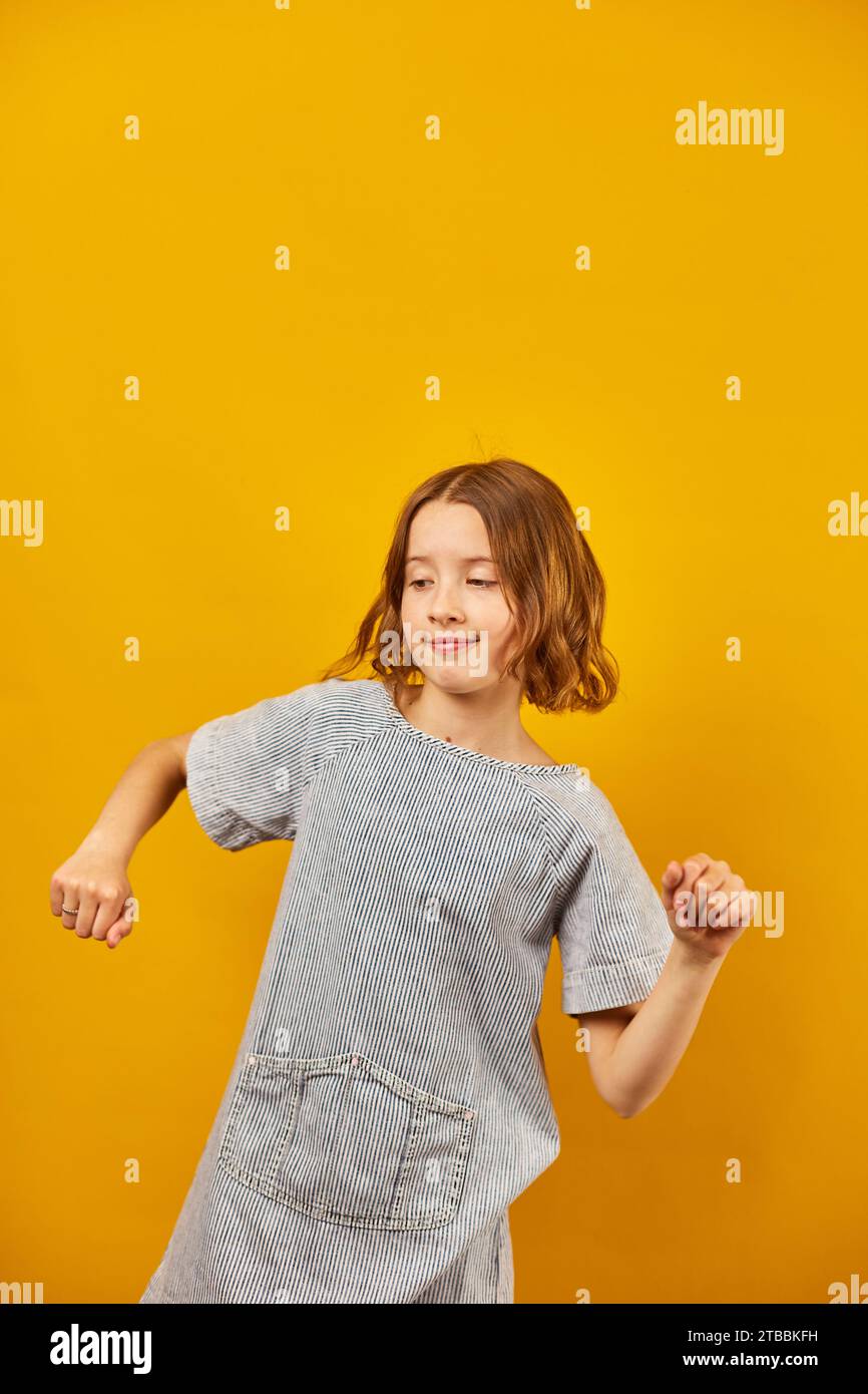 Happy teen girl dancing on yellow studio background Stock Photo - Alamy