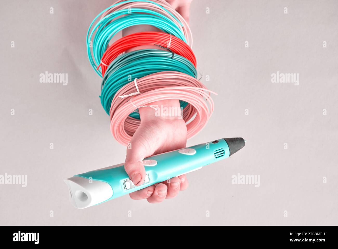Kid hand with modern 3D pen and bunch of colorful plastic strings on ...
